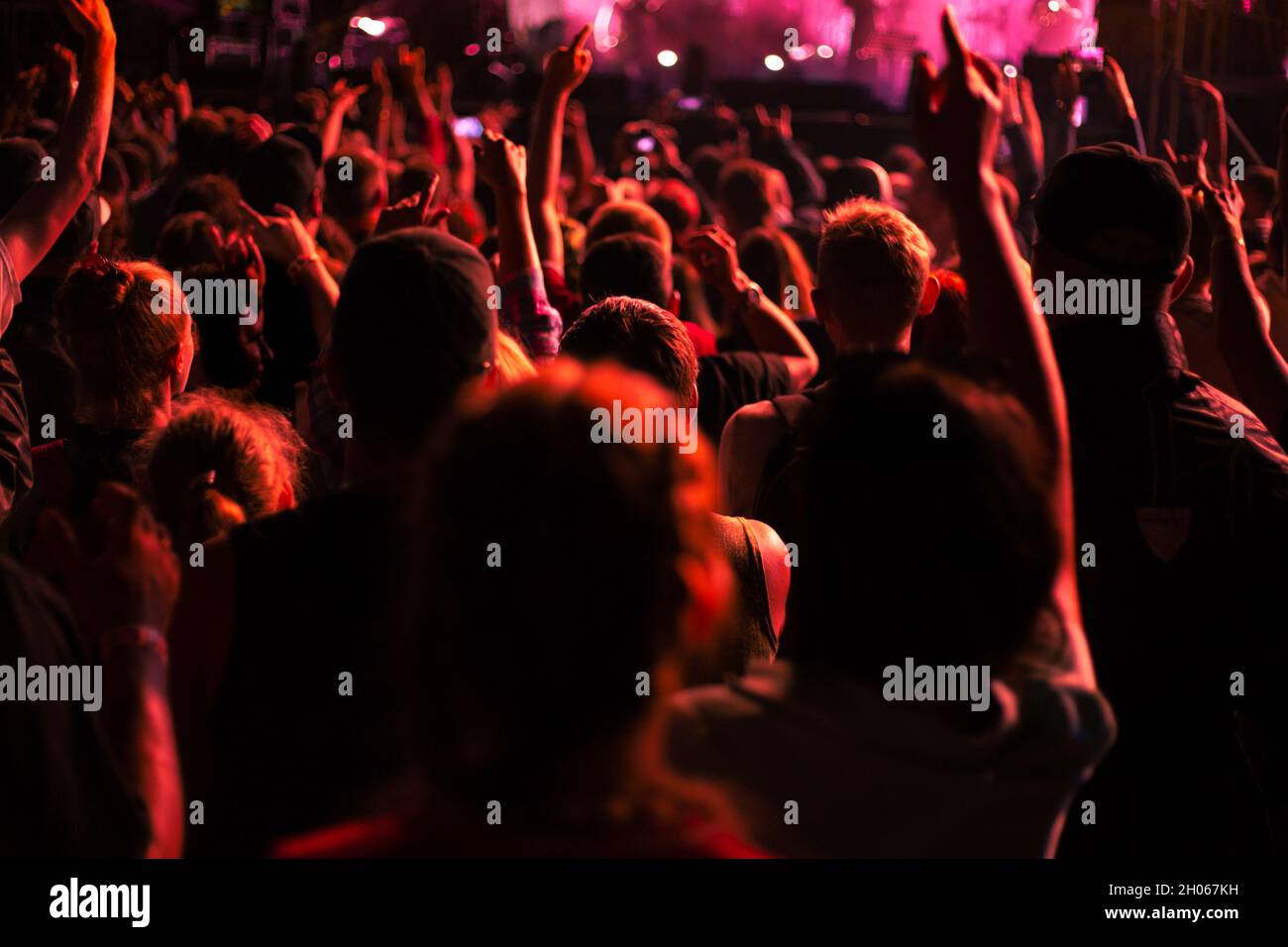 crowd of people with arms raised in the red light of lights Stock Photo ...