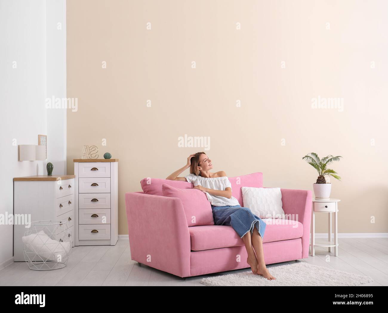 Happy young woman sitting under air conditioner at home Stock Photo - Alamy