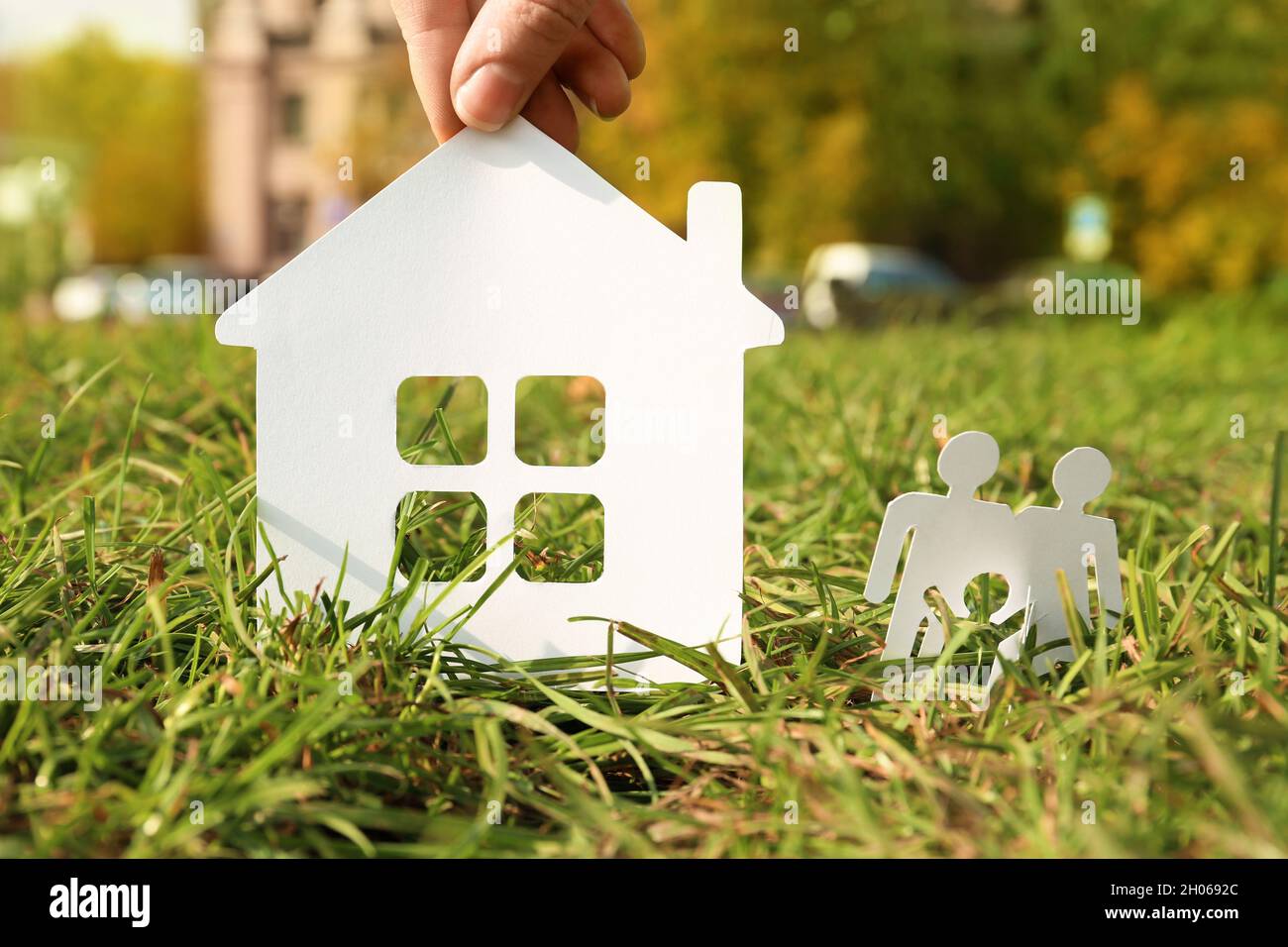 Woman with paper silhouettes of house and family in grass outdoors ...