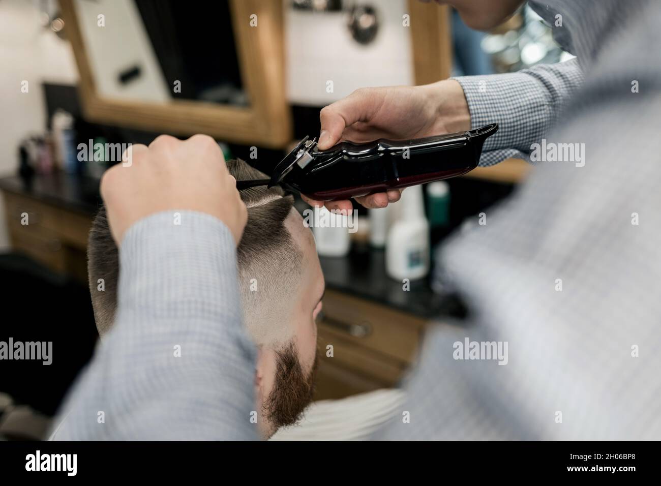 Professional hairdresser doing styling of man with electric hair ...