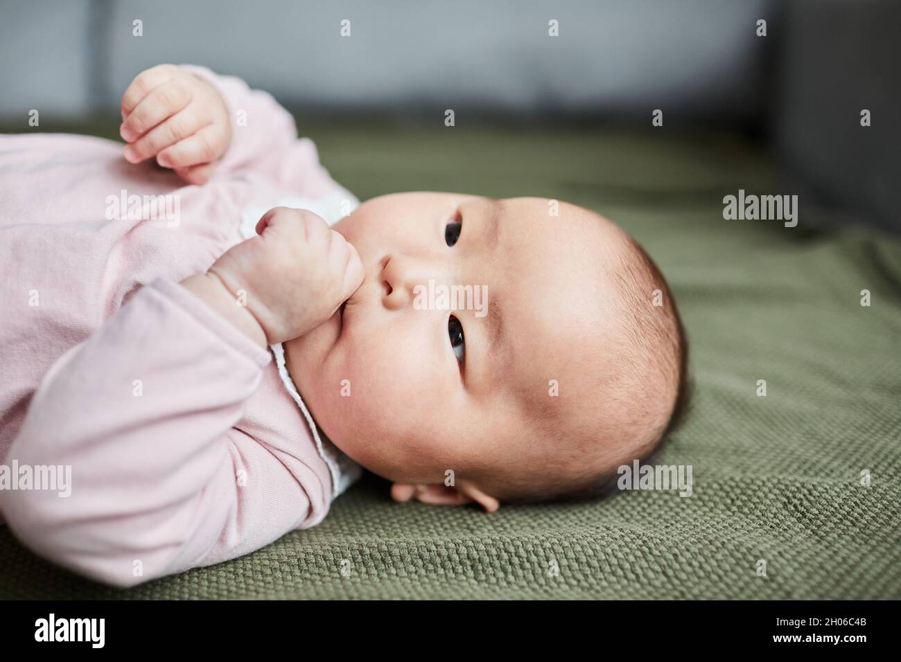 Close-up of little child exploring her hands while lying on the bed ...