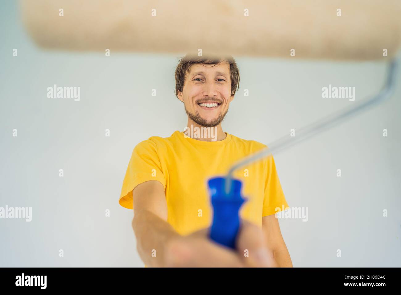 One male house painter worker painting and priming wall with painting ...