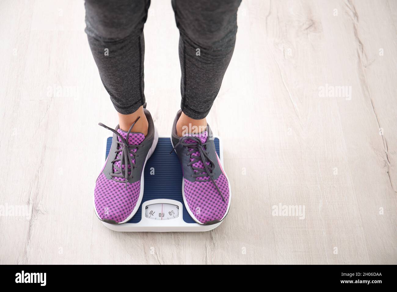 Woman measuring her weight using scales on floor Stock Photo - Alamy