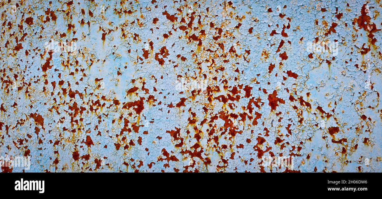 The texture of old peeling paint and bleached rust on a metal plate ...