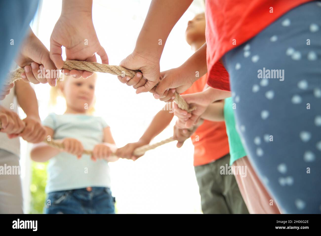 Little children holding rope on light background, focus on hands. Unity ...