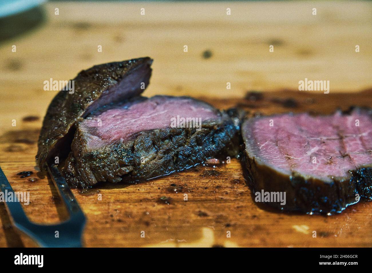 Selective focus shot of a sliced beef fillet in grease on a wooden ...