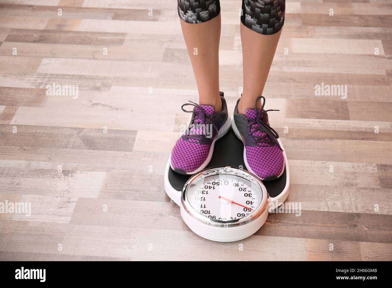 Woman measuring her weight using scales on floor Stock Photo - Alamy