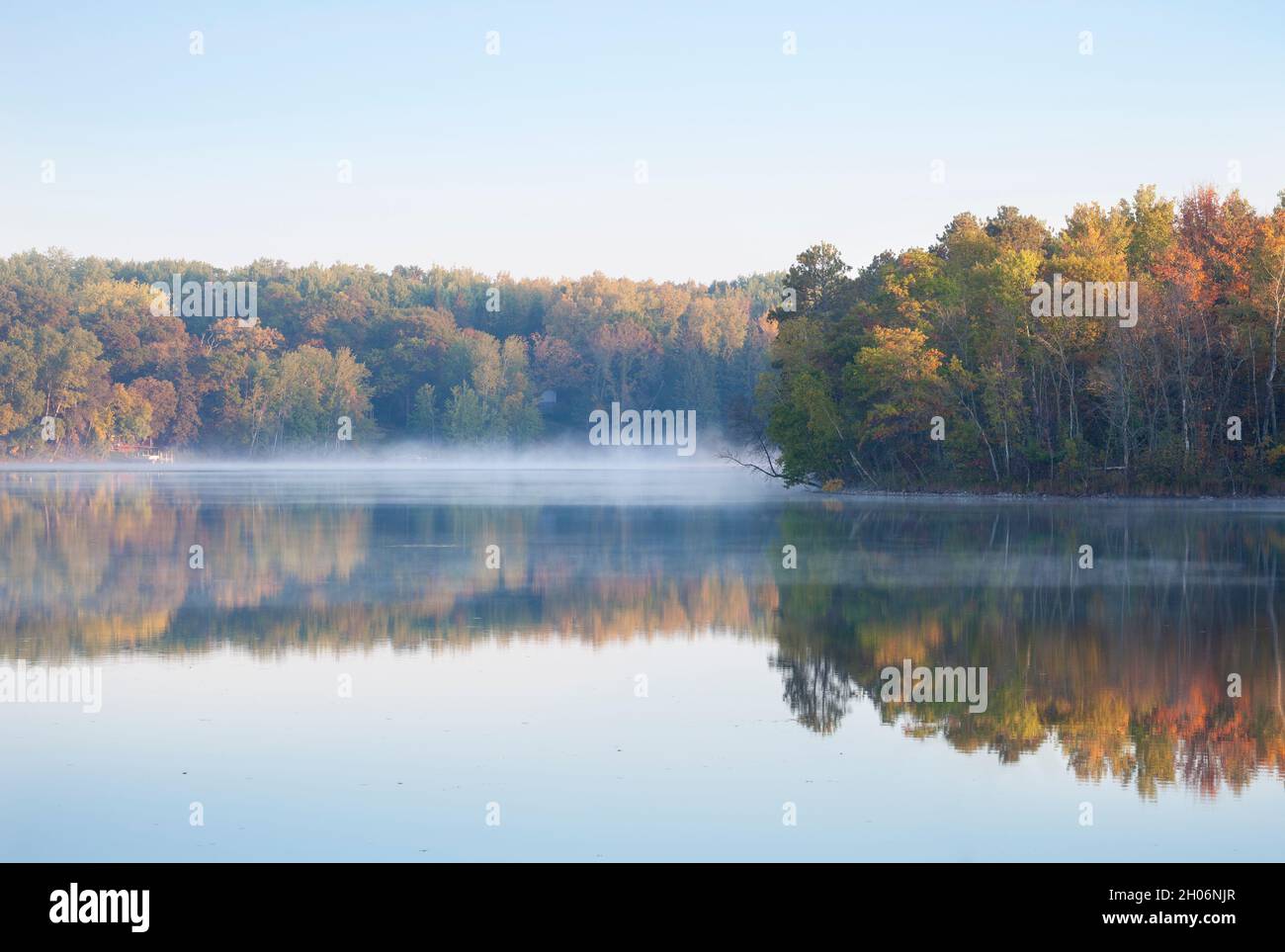 Trees in autumn color on a misty calm lake in northern Minnesota at ...