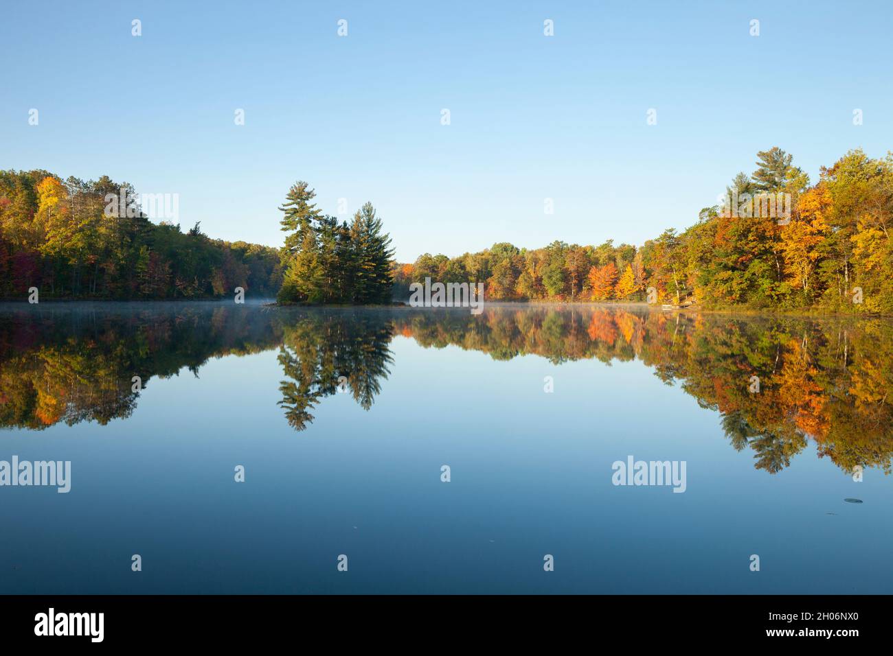 Beautiful lake with trees in autumn color and a small island in ...