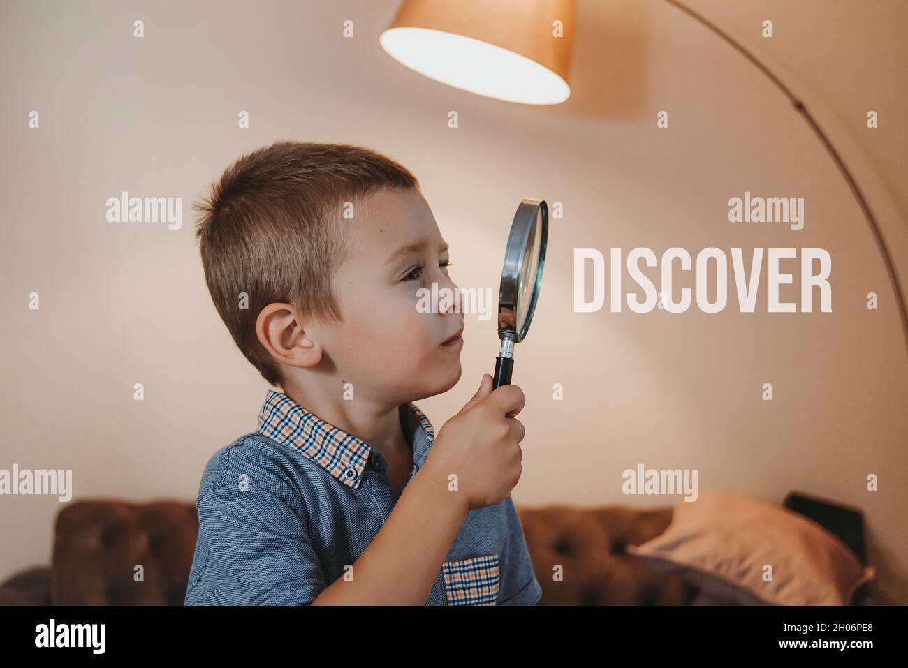 Boy looking through magnifier at the word Discover Stock Photo - Alamy
