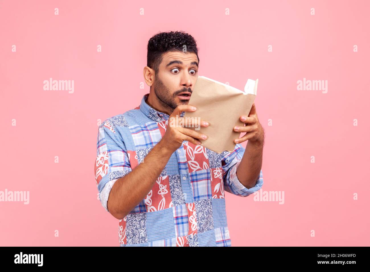 Shocking facts. Astonished smart bearded man reading book with ...