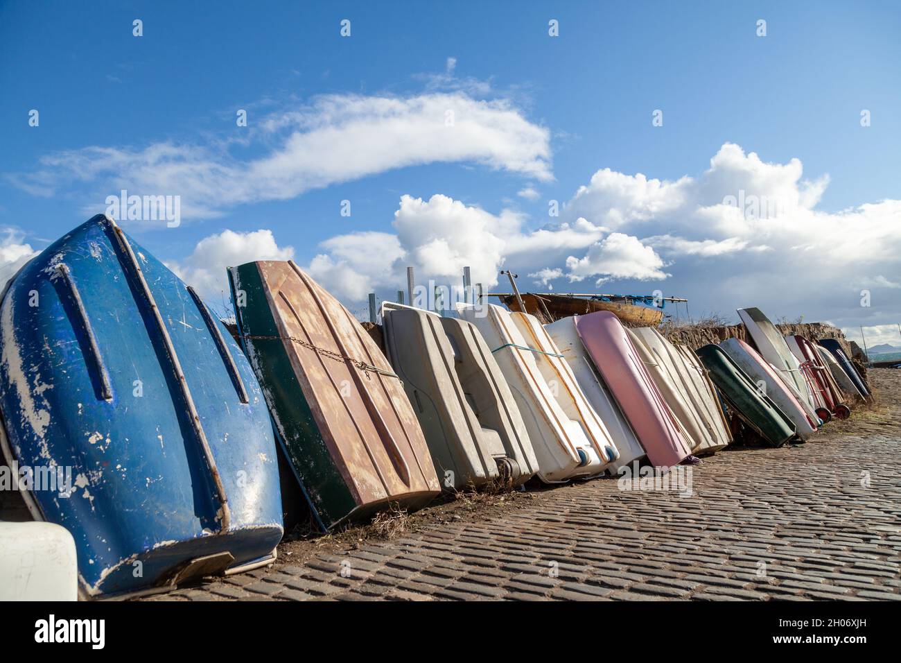 Rowing boats leaning against a harbour wall in Dysart, Fife, Scotland ...
