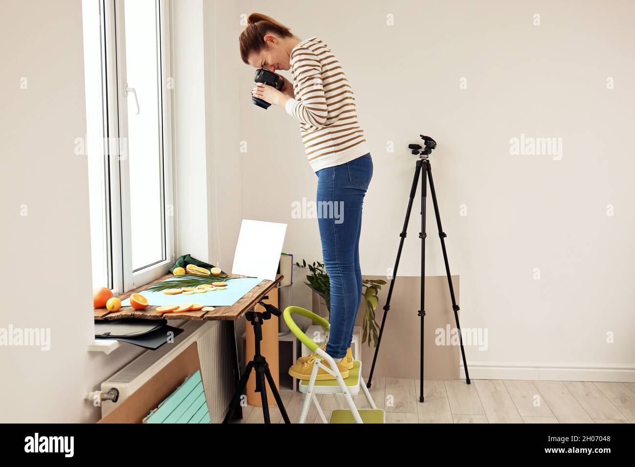 Woman taking picture of cut fruits and palm leaf on window sill. Food ...