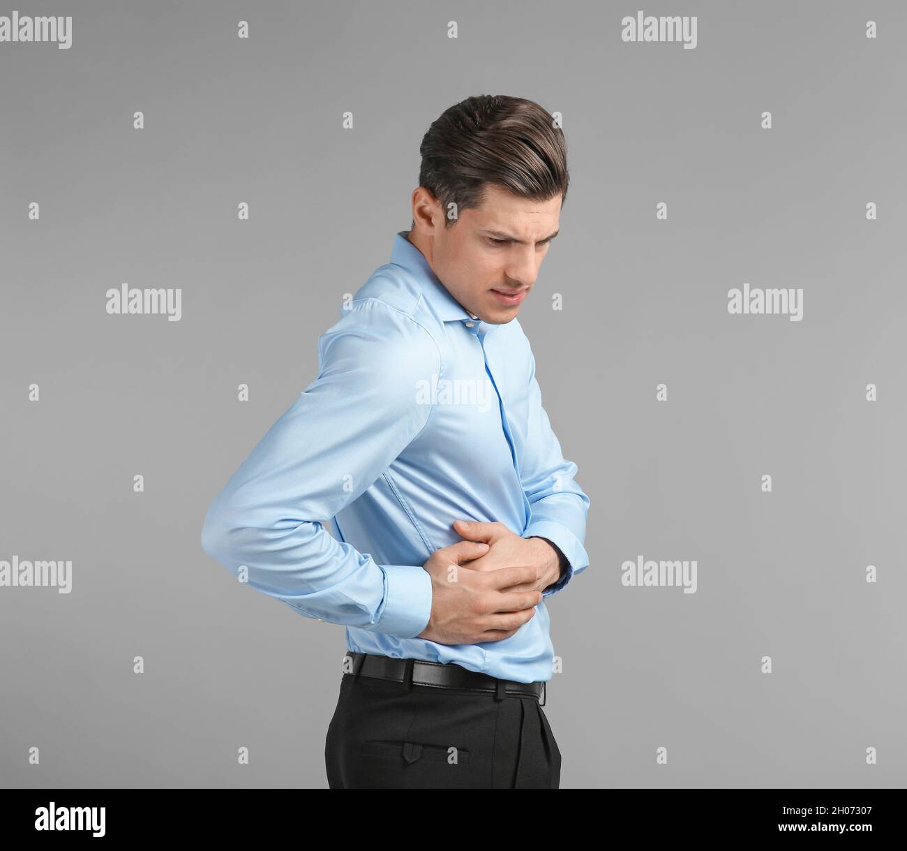 Young man suffering from flank pain on grey background Stock Photo - Alamy