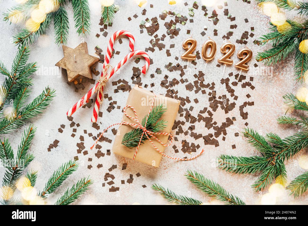 Golden 2022 candle numbers with fir tree branches, Christmas decorations and Christmas lights ...