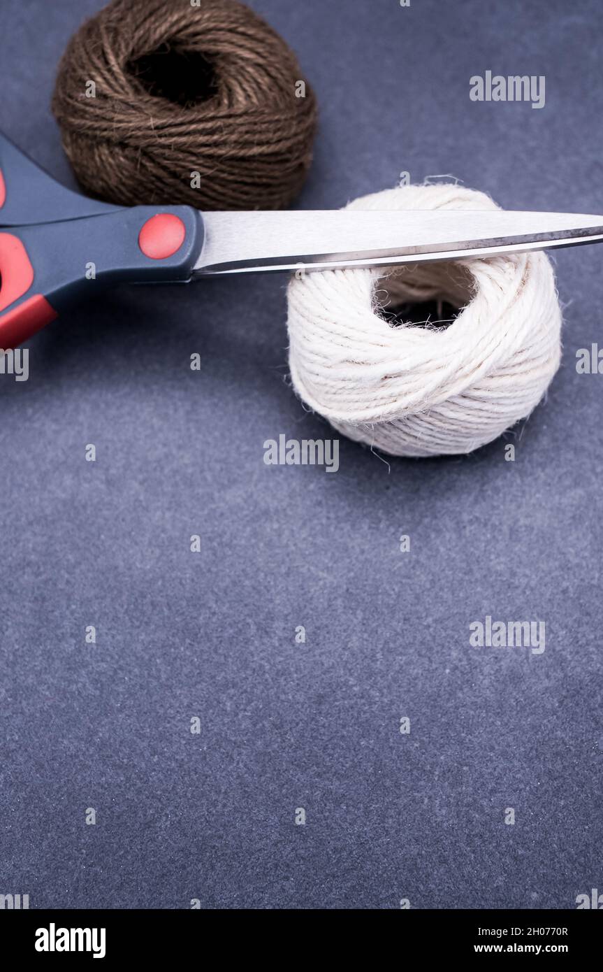 A closeup shot of rough decoration yarns and scissors on a dark stone ...