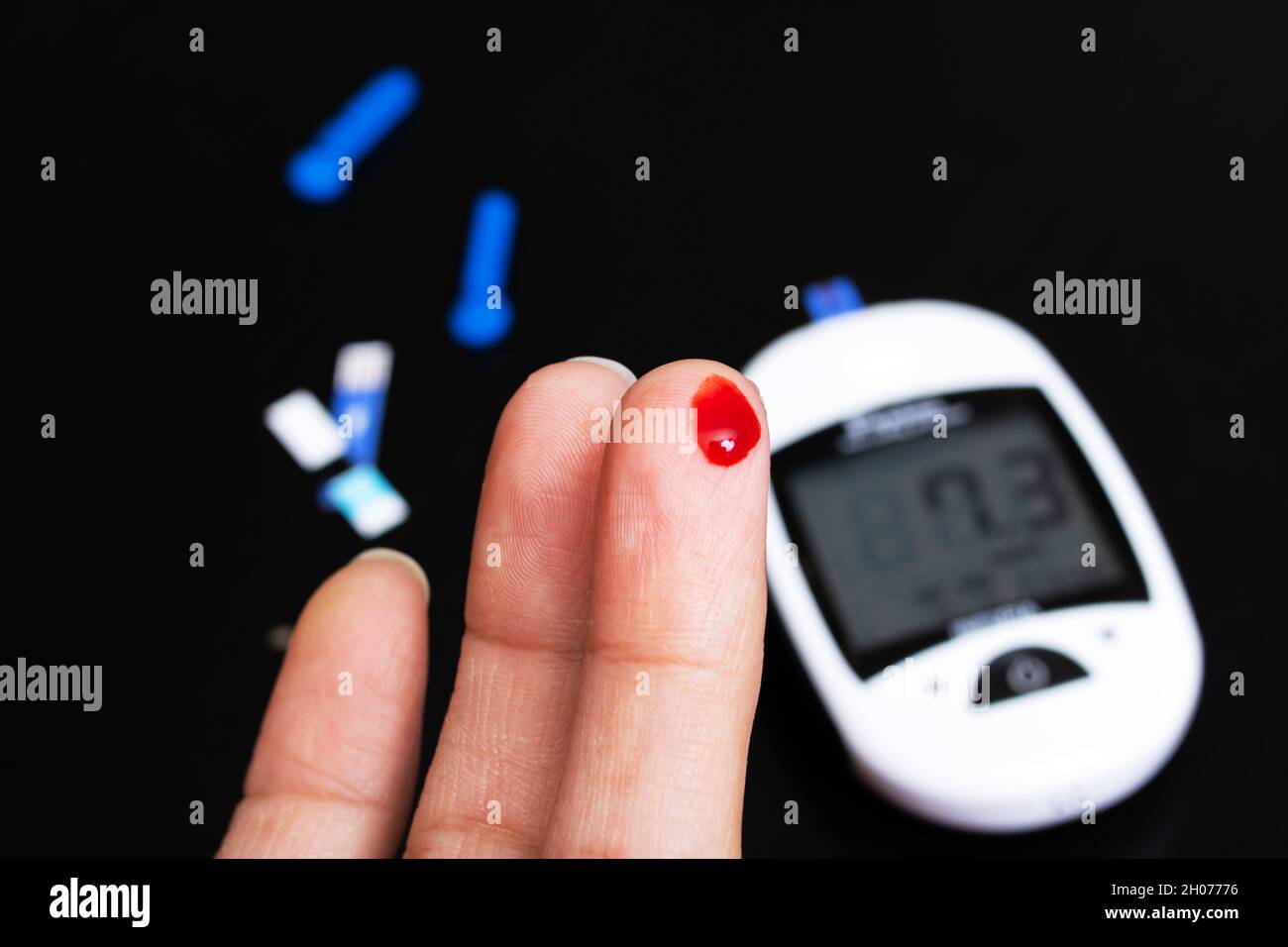 Elevated blood sugar on the glucometer monitor and a finger with blood ...