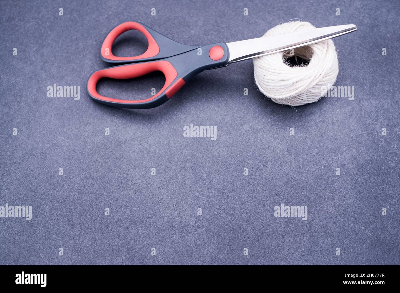 A closeup shot of rough decoration yarns and scissors on a dark stone ...