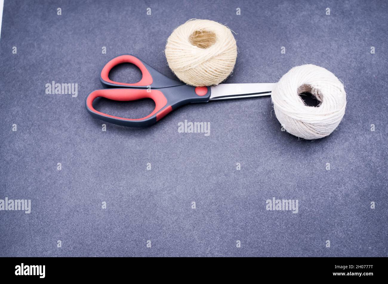 A closeup shot of rough decoration yarns and scissors on a dark stone ...