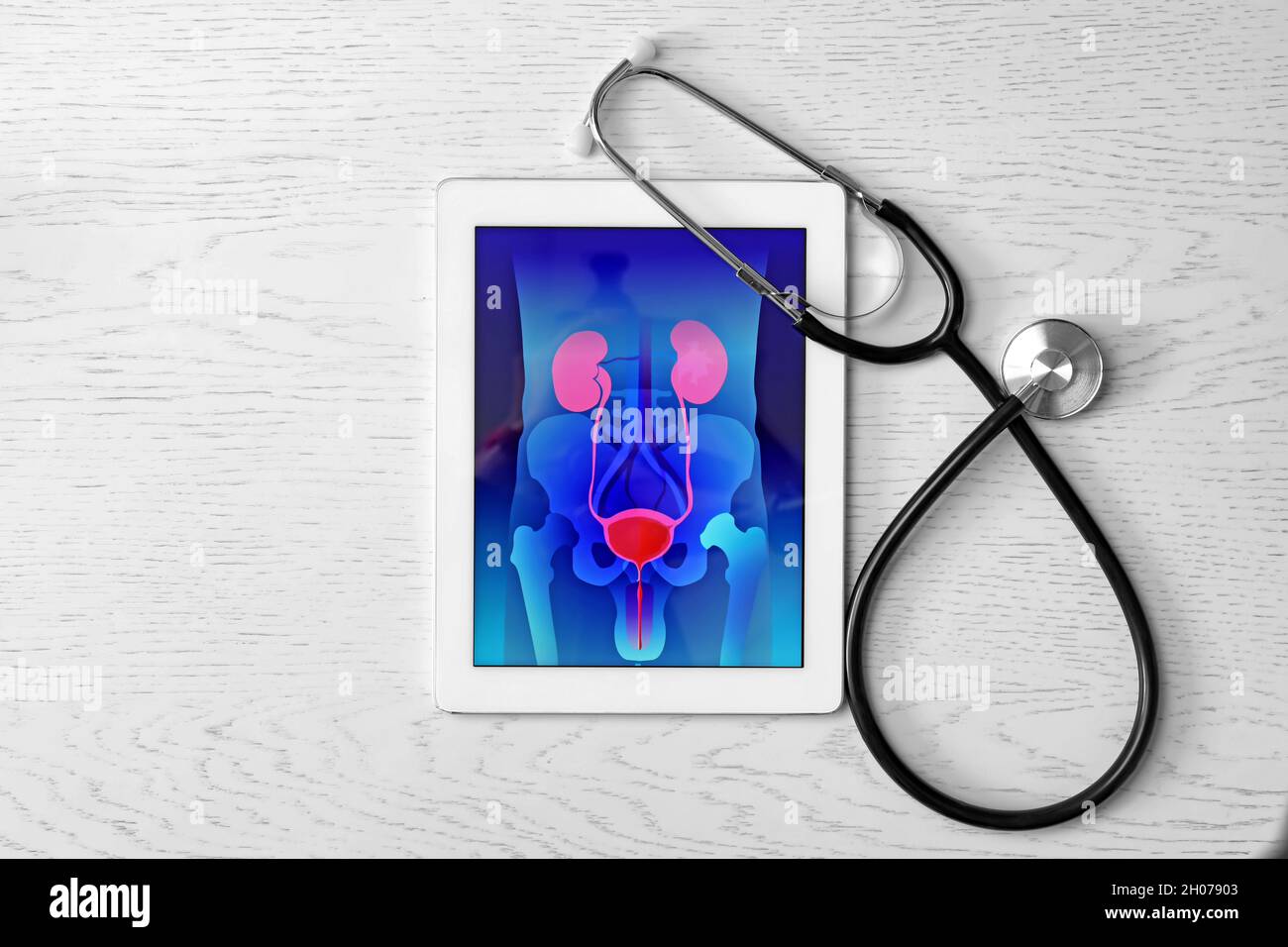 Tablet displaying urinary system and stethoscope on wooden background ...
