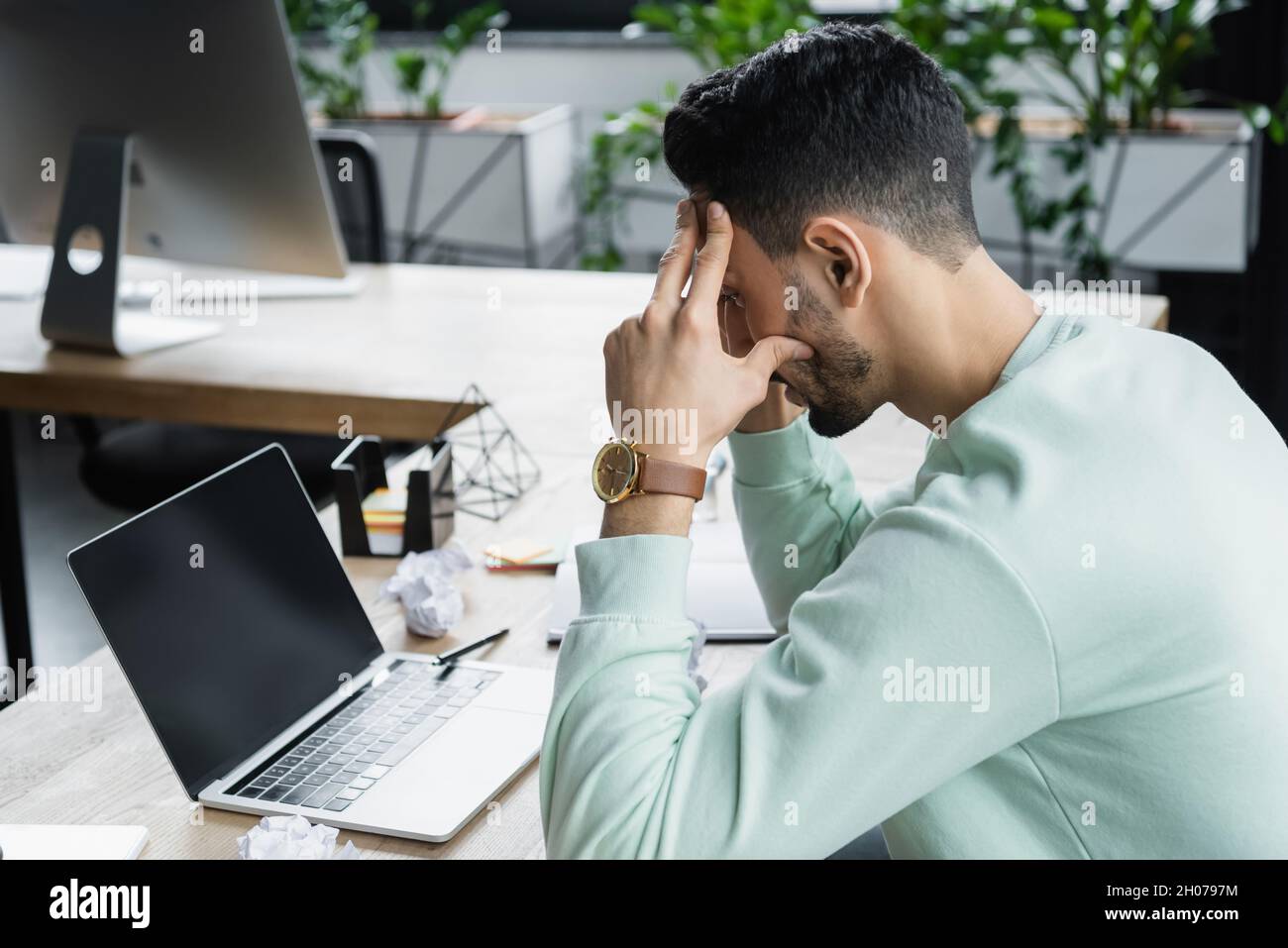 Side view of muslim businessman looking at laptop with blank screen ...