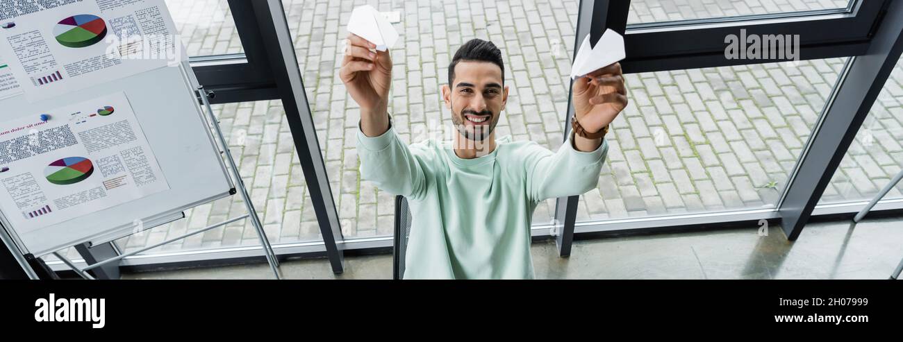 High angle view of arabian businessman with paper planes smiling at ...