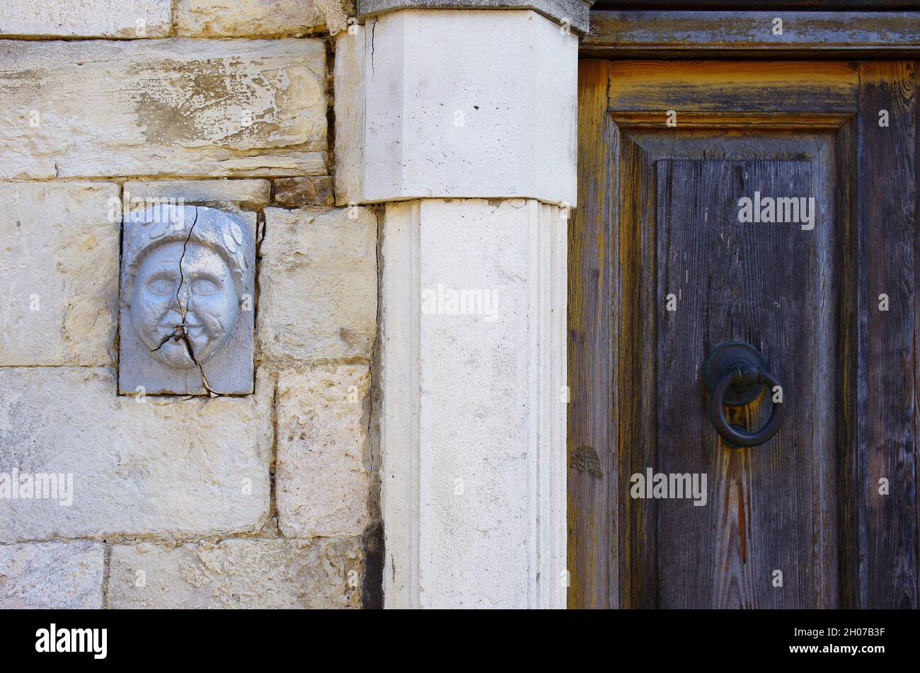 An ancient decoration set between the stones of a wall and a door of an ...