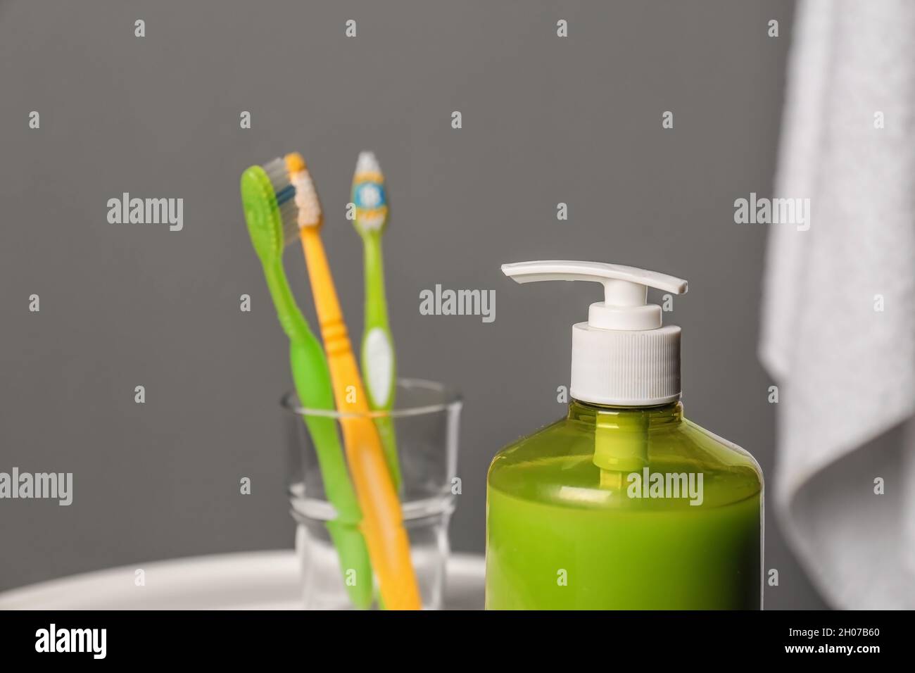 Glass with toothbrushes and bottle of liquid soap in bathroom Stock ...