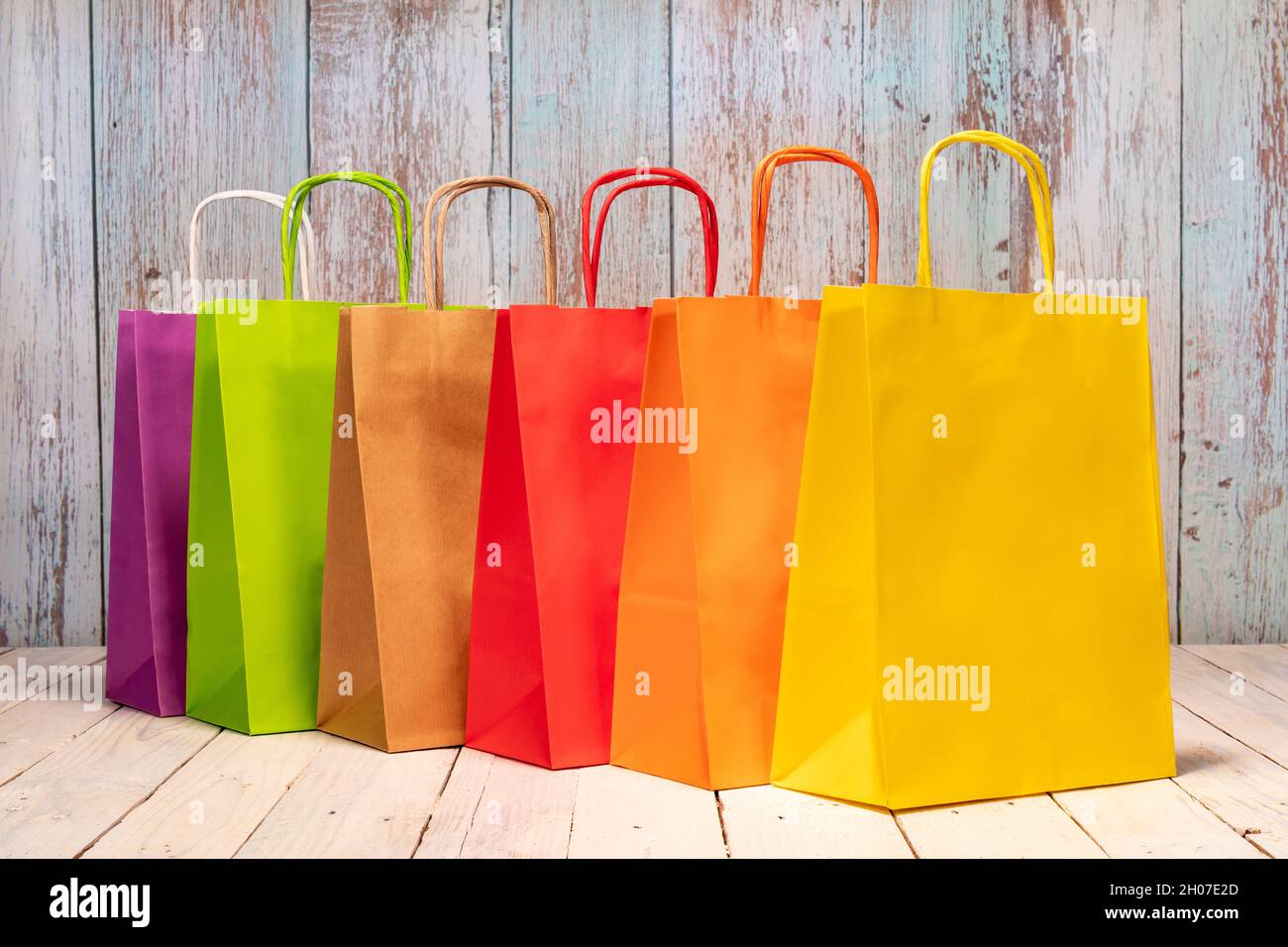 A rainbow of colorful paper bags on a shabby chic wooden table for your ...
