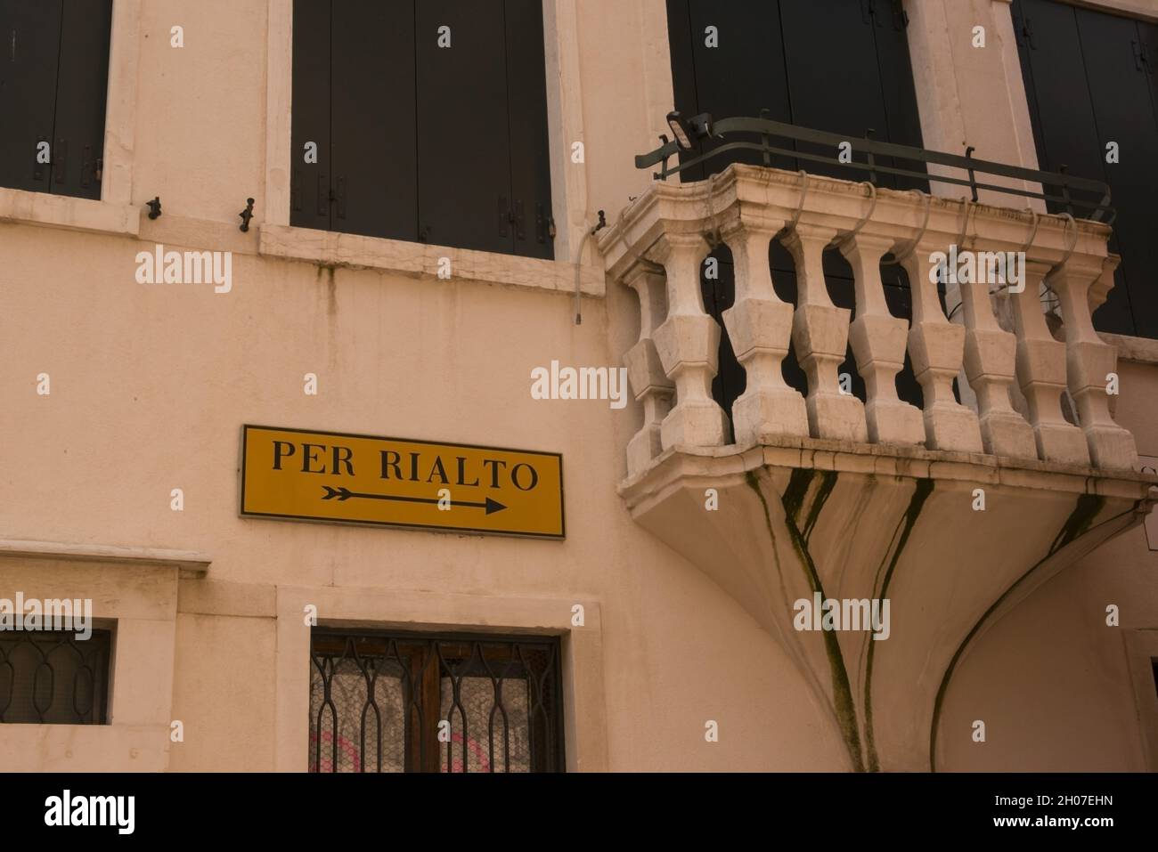 old balcony next to a typical signpost to the Rialto bridge in Venice ...