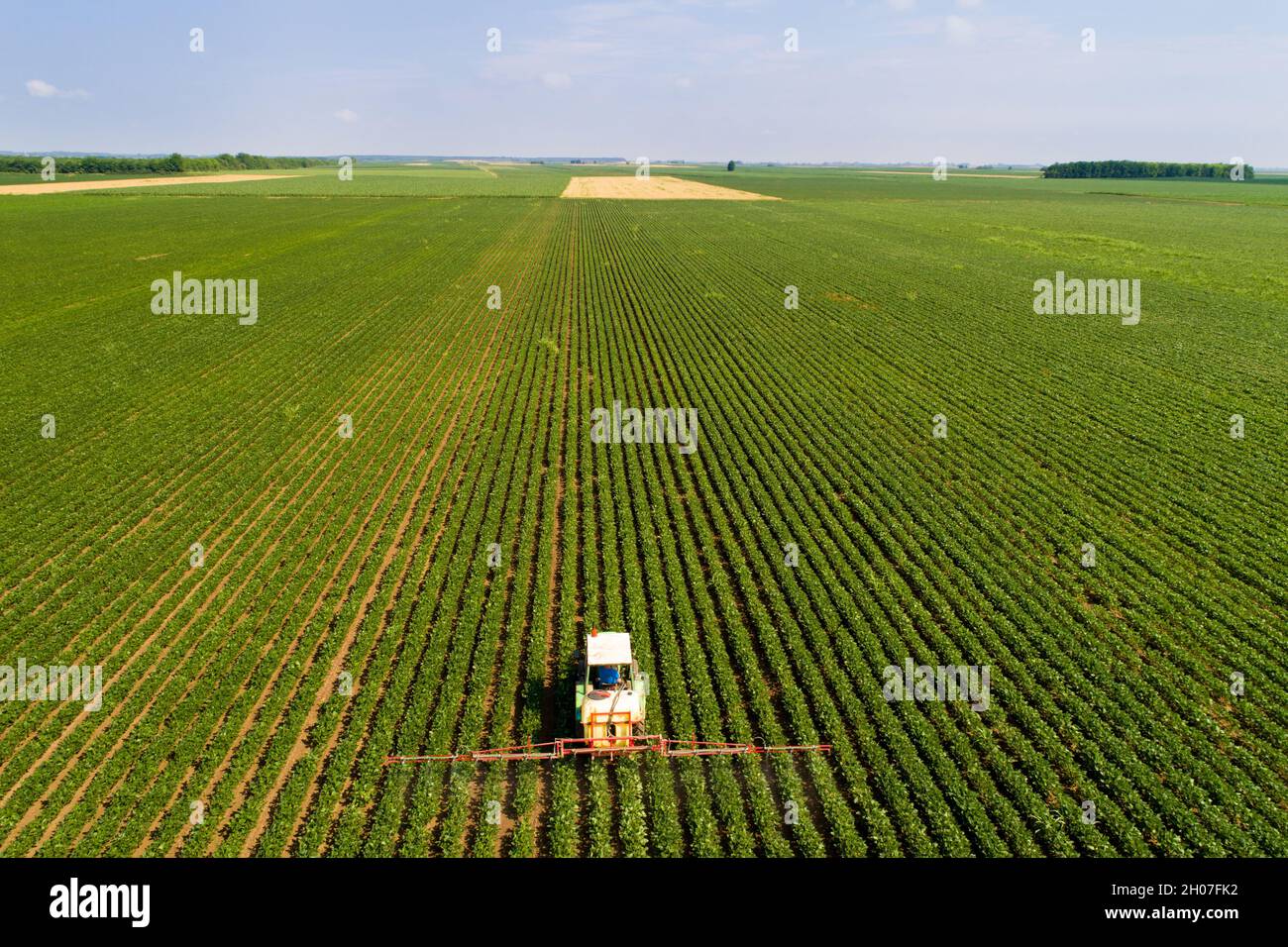 Aerial image of tractor spraying soybean field in early summer shoot ...