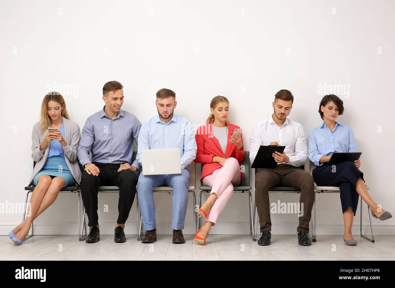 Group of young people waiting for job interview near light wall Stock ...
