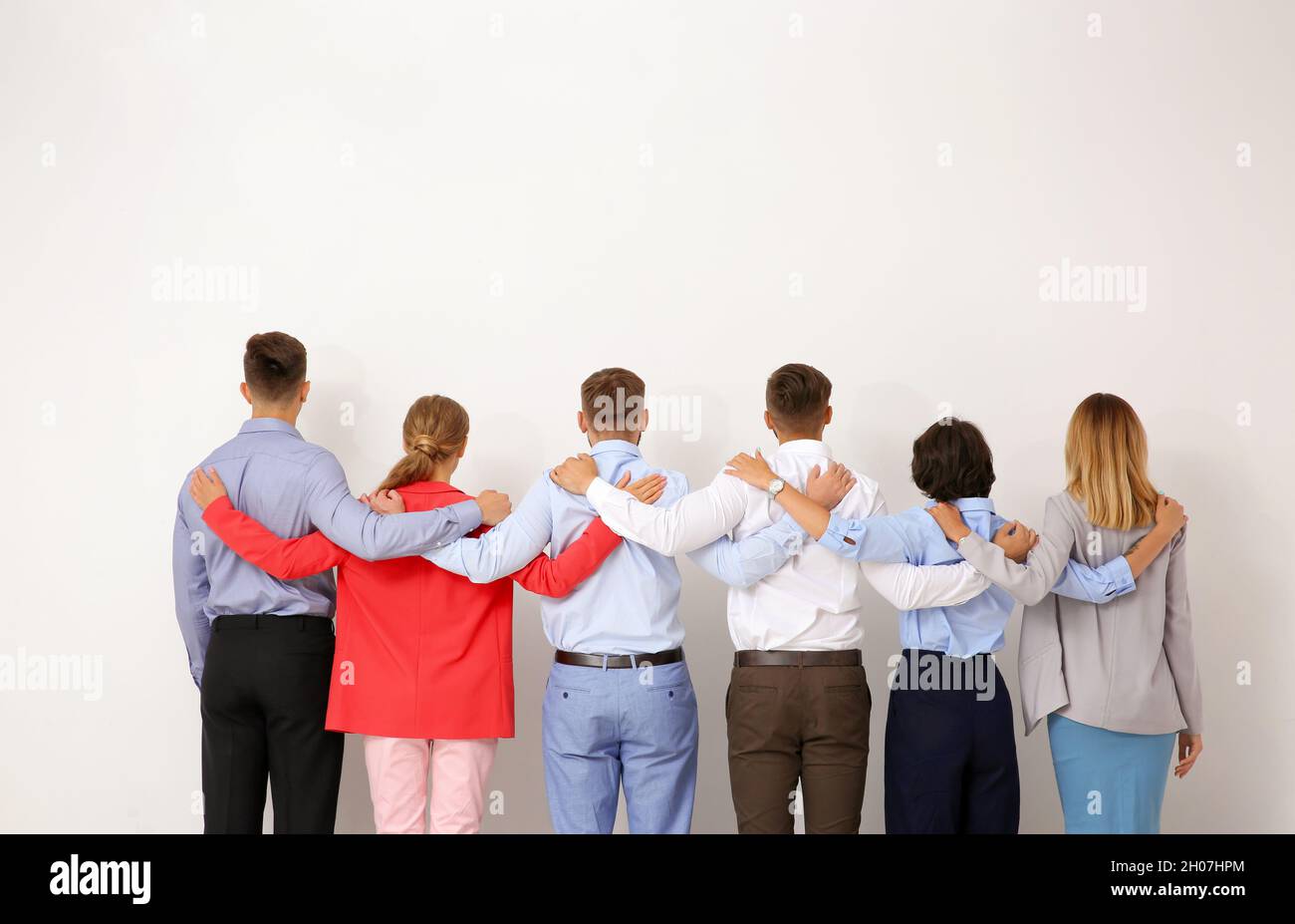 Group of young people hugging each other on light background. Teamwork ...