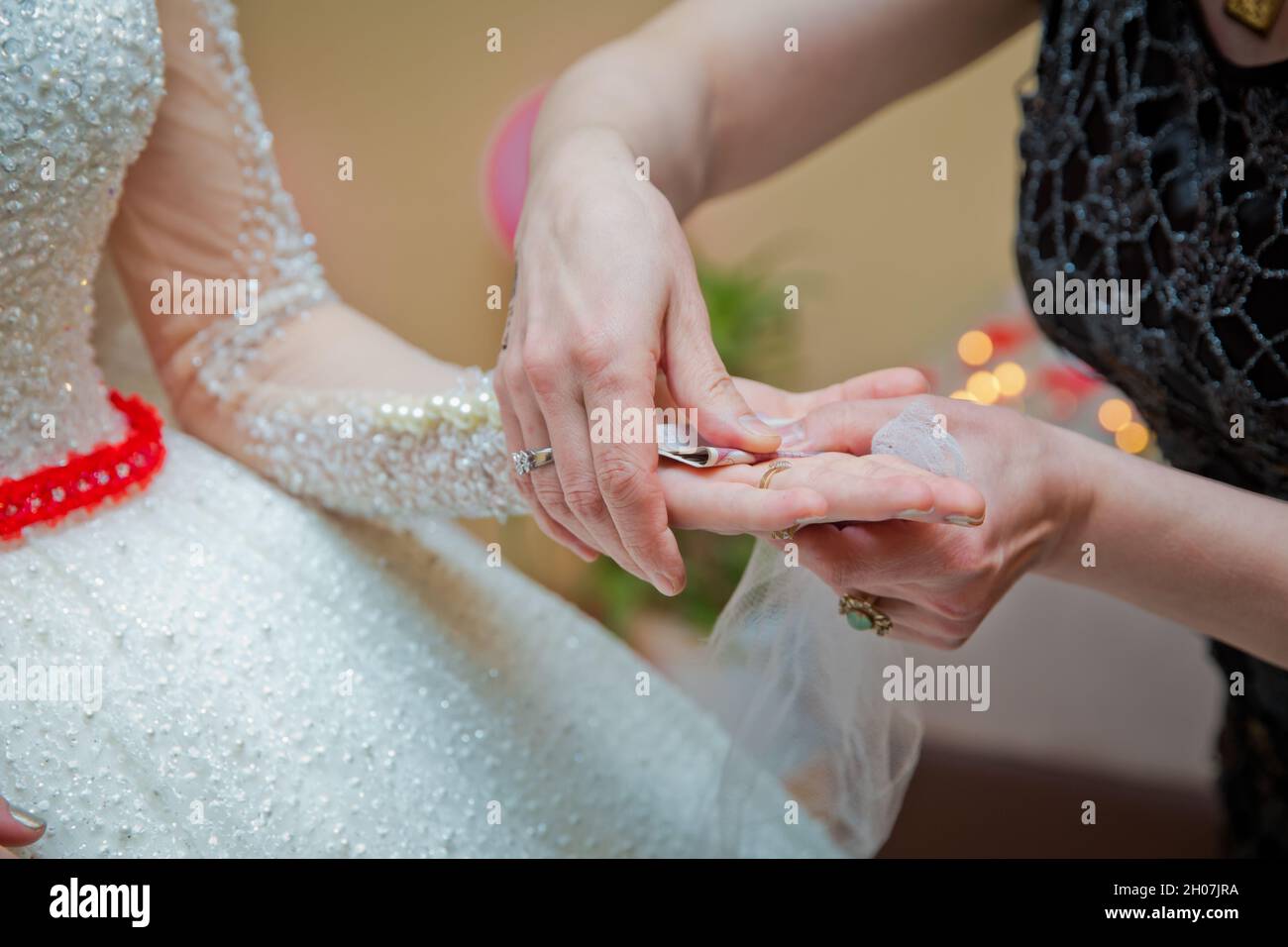 The bride ties a ribbon and money over her hand . He ties a ribbon and ...