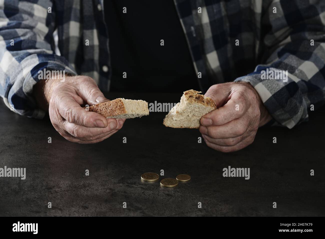 Poor elderly man with bread at table, focus on hands Stock Photo - Alamy