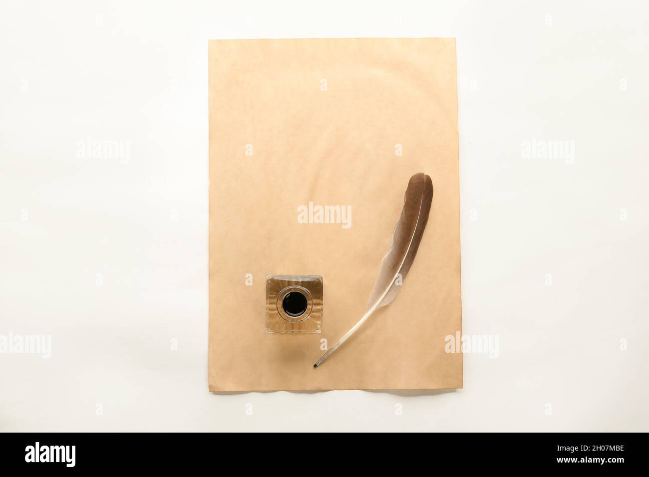 Feather pen, inkwell and sheet of paper on white background, top view ...