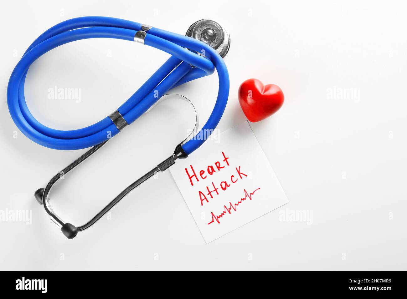 Stethoscope, note with phrase "HEART ATTACK" and small red heart on ...
