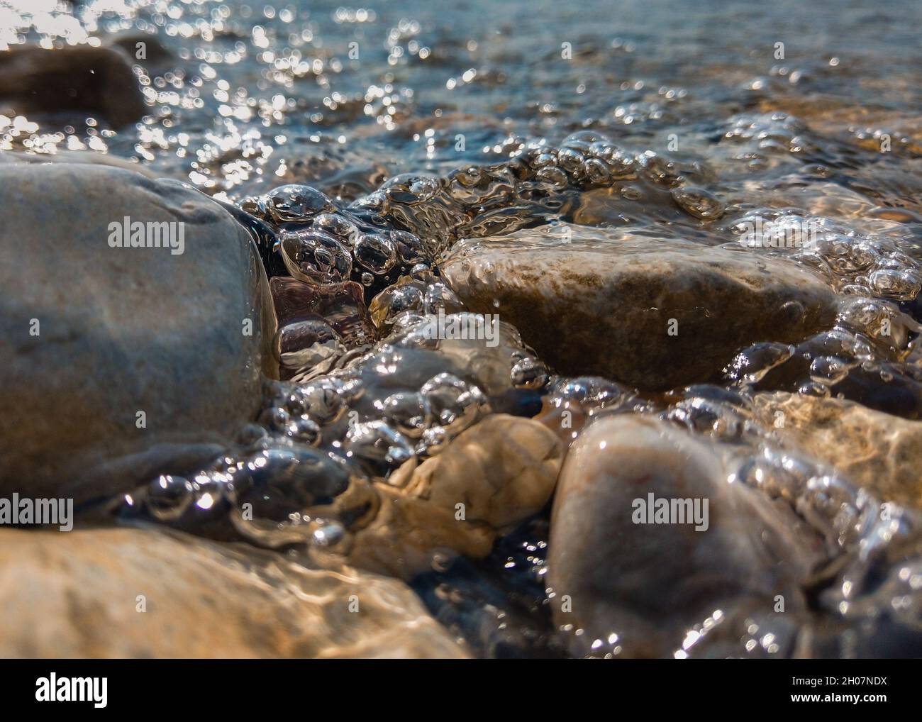 Waves on a stone beach, the texture of the transparent clear waters of ...