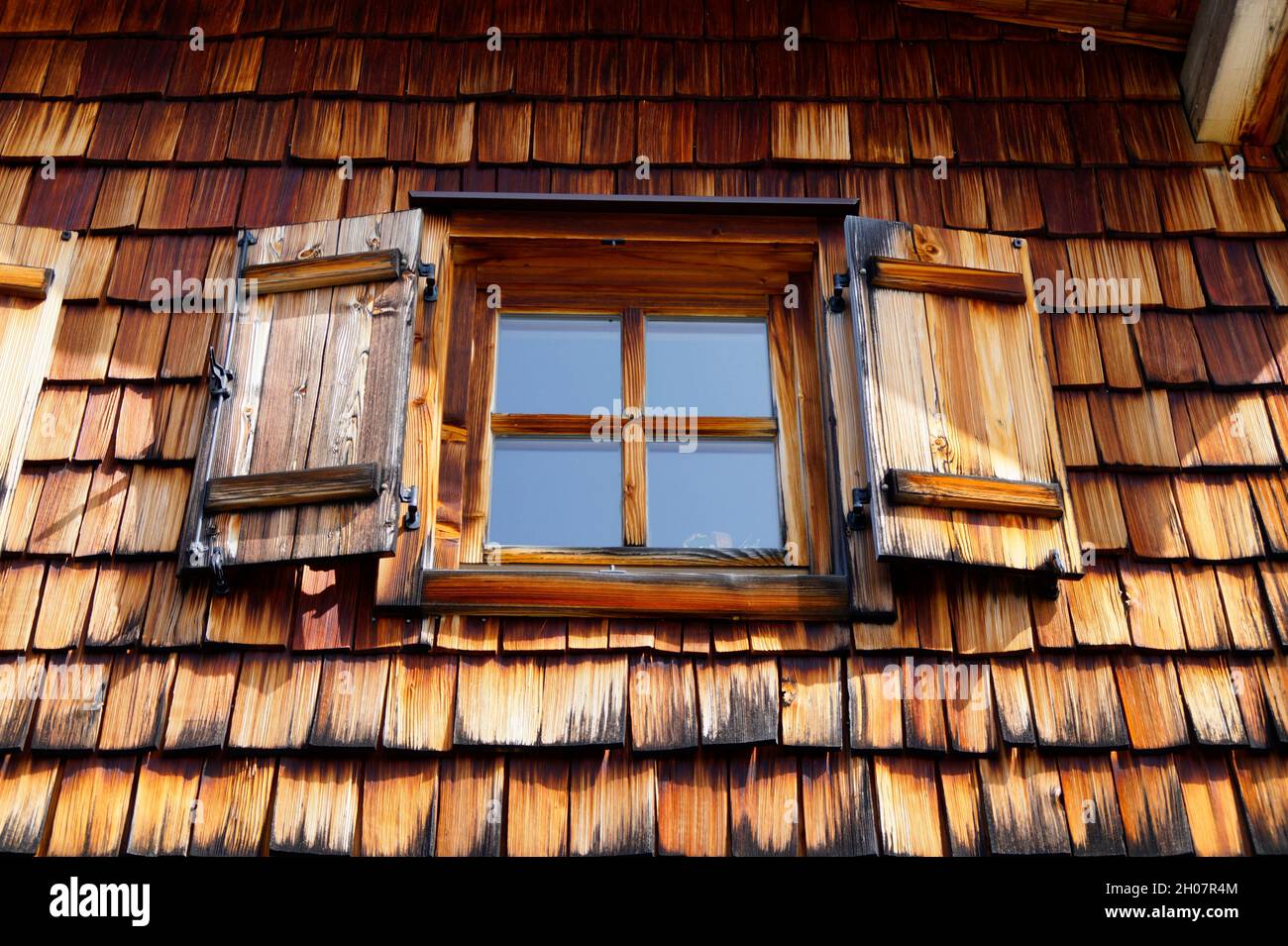 a window with wooden shutters of a rustic wooden cabin in the Austrian ...