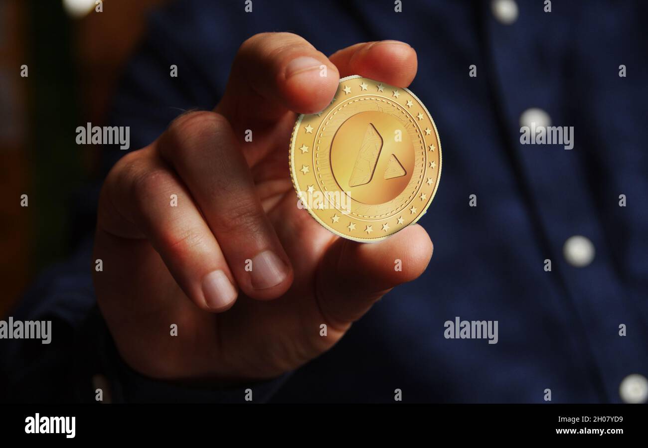 Avalanche AVAX cryptocurrency symbol golden coin in hand abstract ...