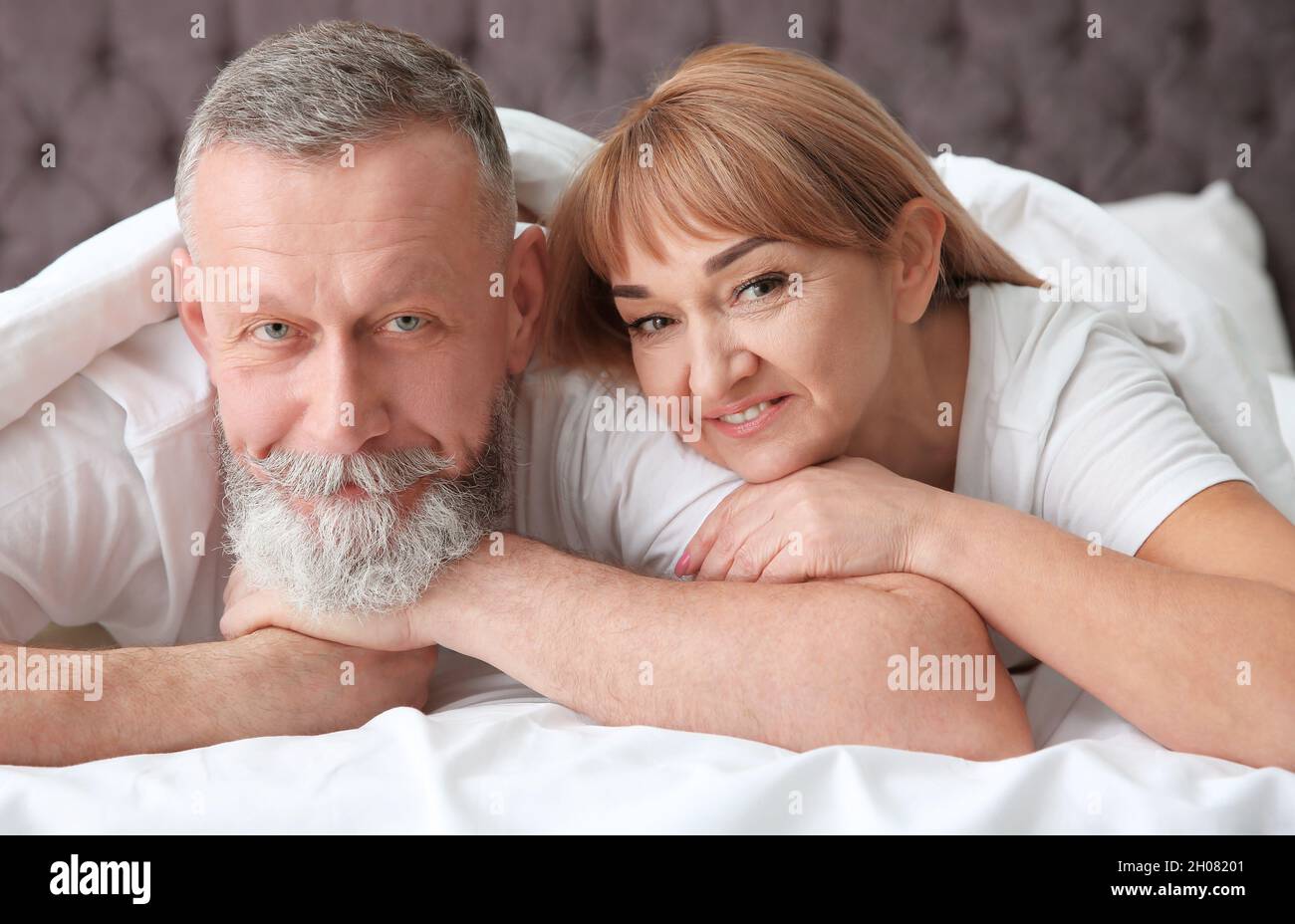 Mature couple together under blanket in bed at home Stock Photo - Alamy