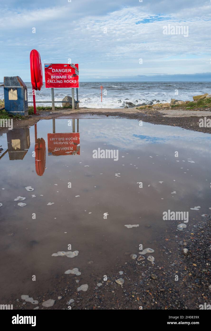 Danger, beware of falling rocks sign at the coastal village of ...