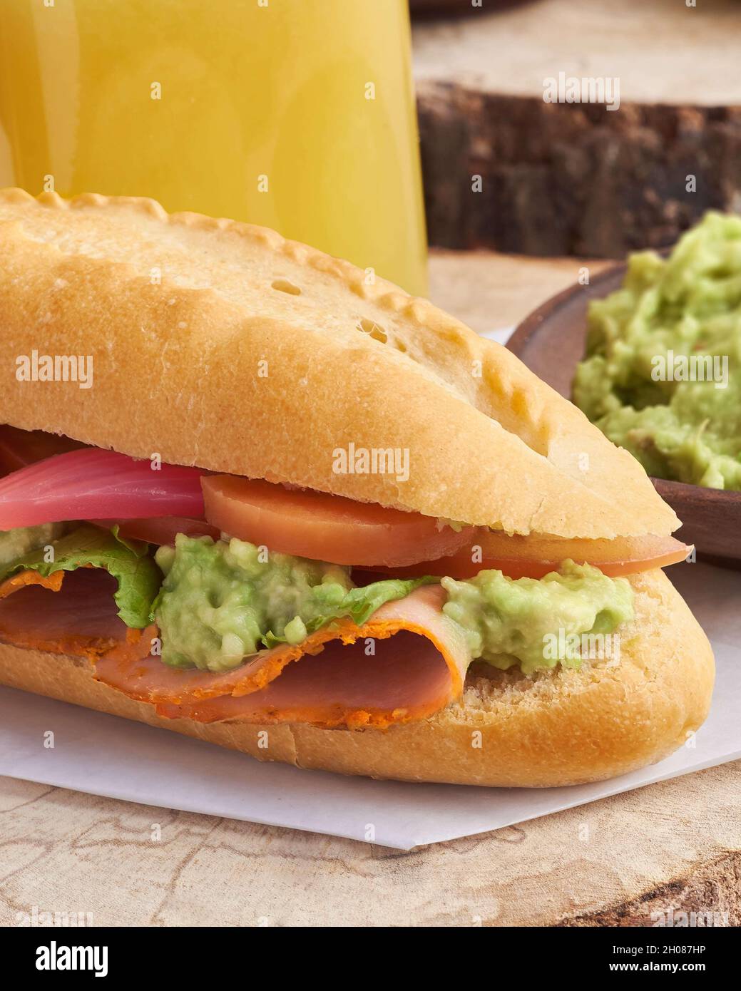 Pork leg sandwich and guacamole sauce served with orange juice Stock ...