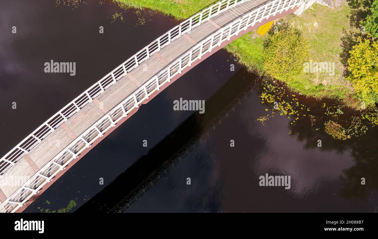 Arching bridge over a deep blue river in greenery Stock Photo - Alamy