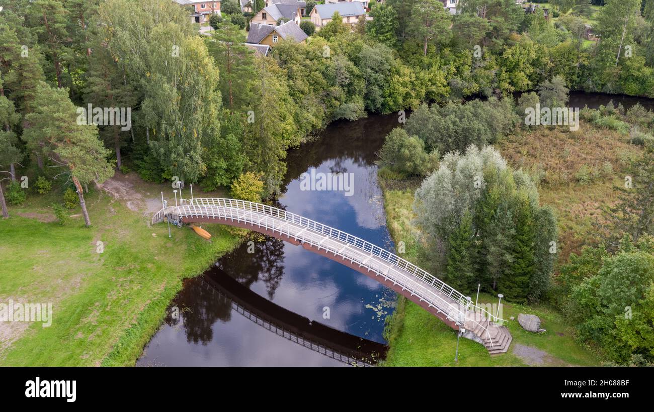 Arching bridge over a deep blue river in greenery Stock Photo - Alamy