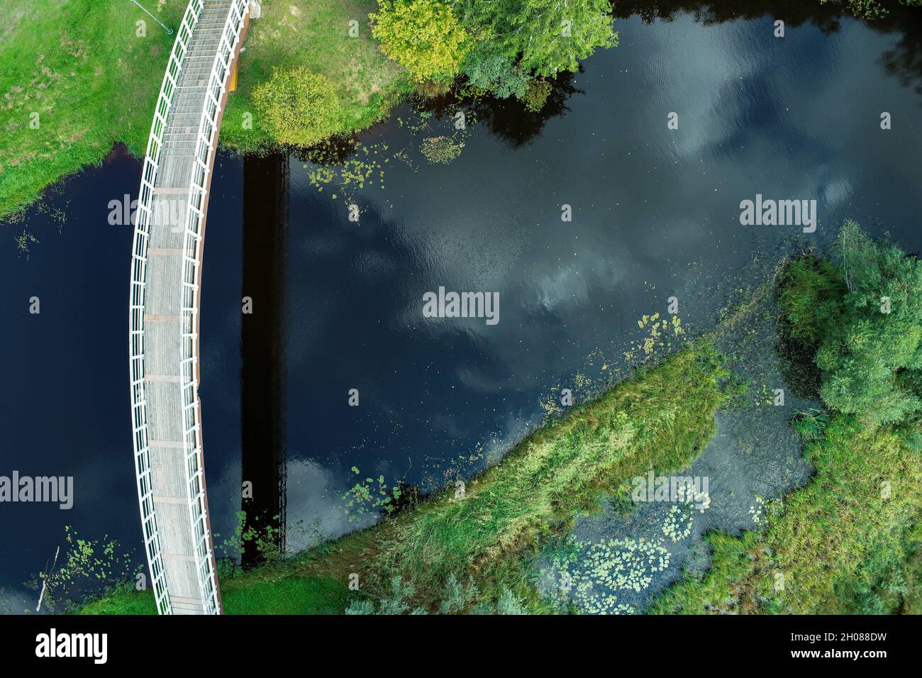 Arching bridge over a deep blue river in greenery Stock Photo - Alamy
