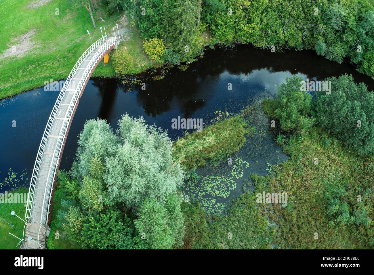 Arching bridge over a deep blue river in greenery Stock Photo - Alamy