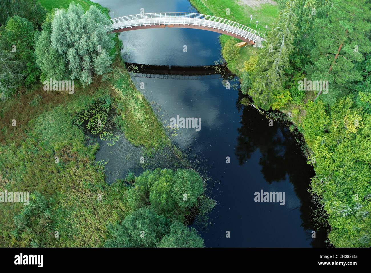 Arching bridge over a deep blue river in greenery Stock Photo - Alamy