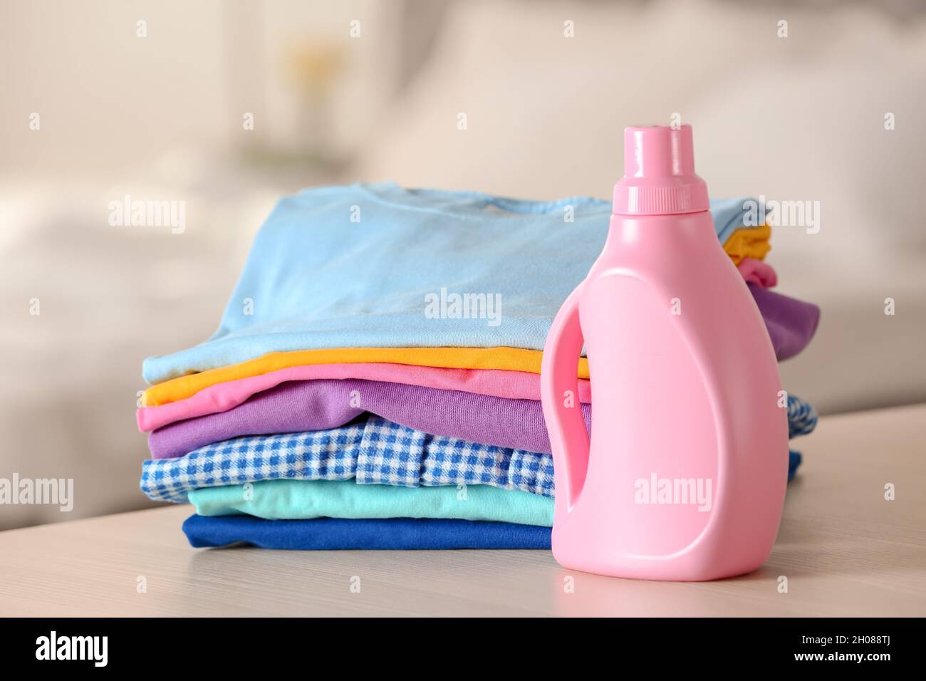 Stack of clean clothes and bottle with detergent on table Stock Photo ...