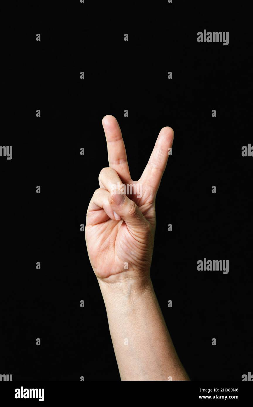 Vertical shot of a hand showing peace sign on a dark background Stock ...